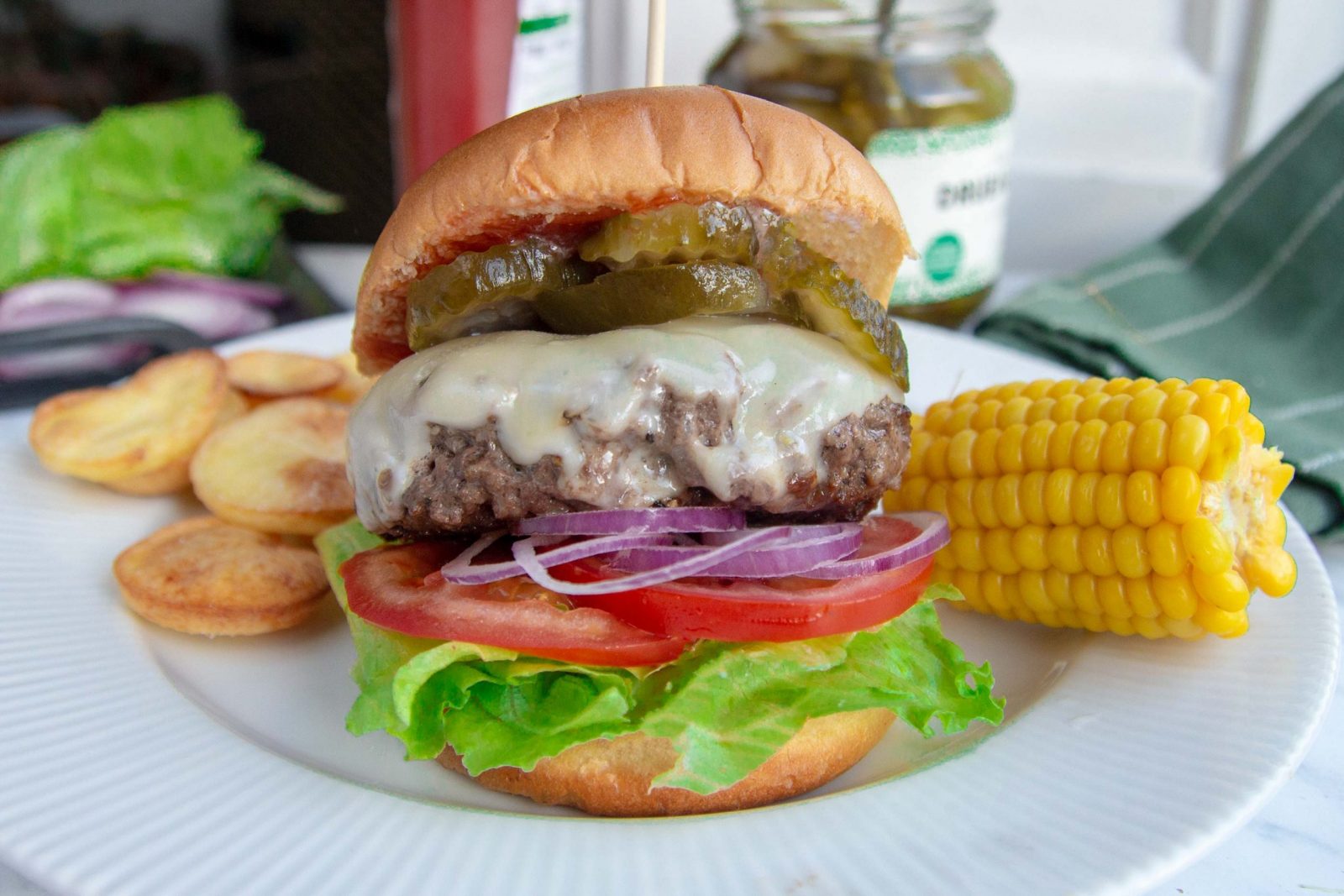 Classic cheeseburgers with potato slices and corn cobs